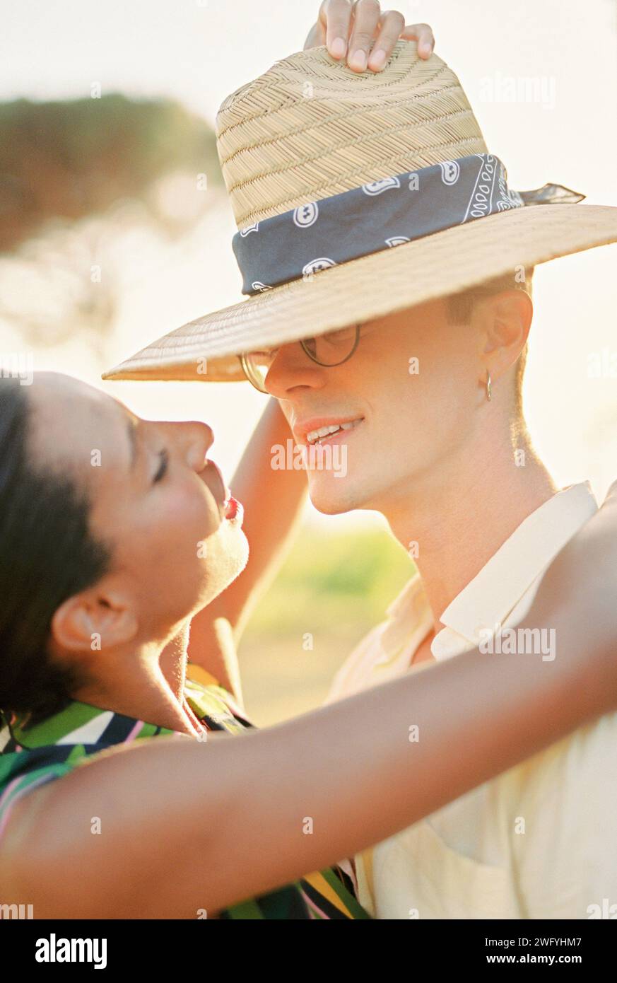 Young woman puts a straw hat on man head while hugging his neck Stock ...