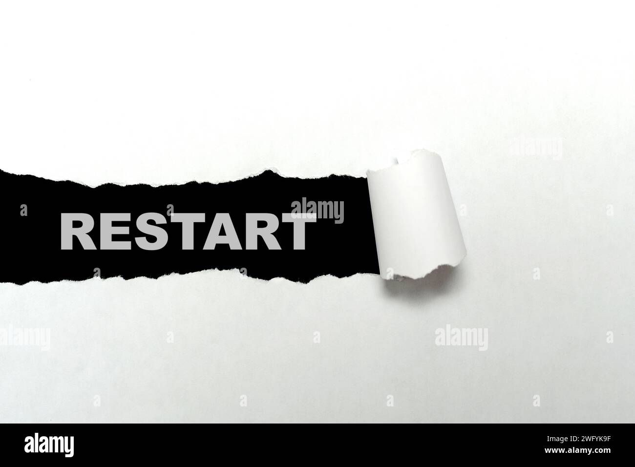 Ripped paper with restart text over a black background. New beginning ...