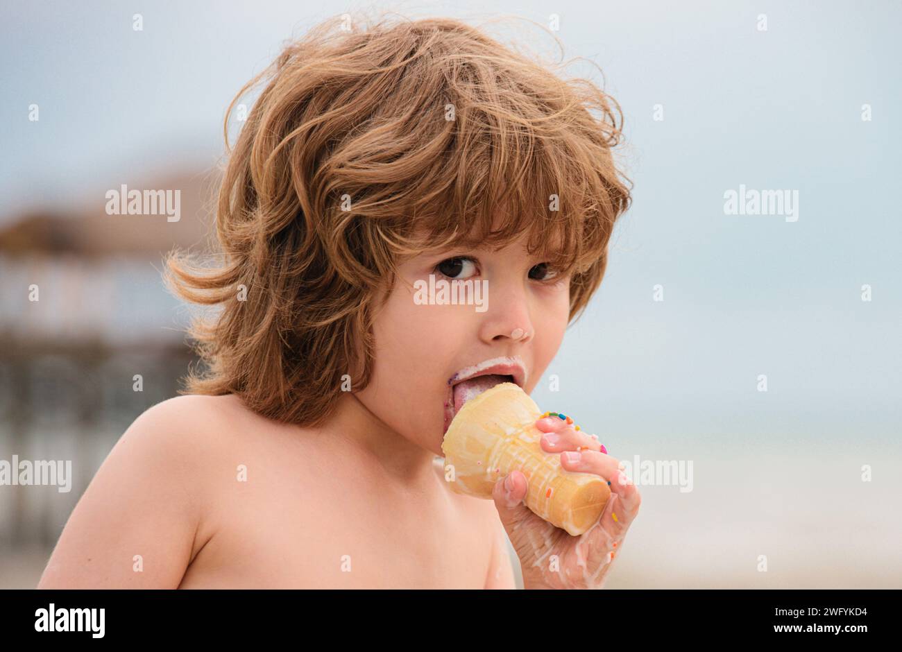 Outdoor closeup portrait of cute kid eating ice cream in summer hot ...