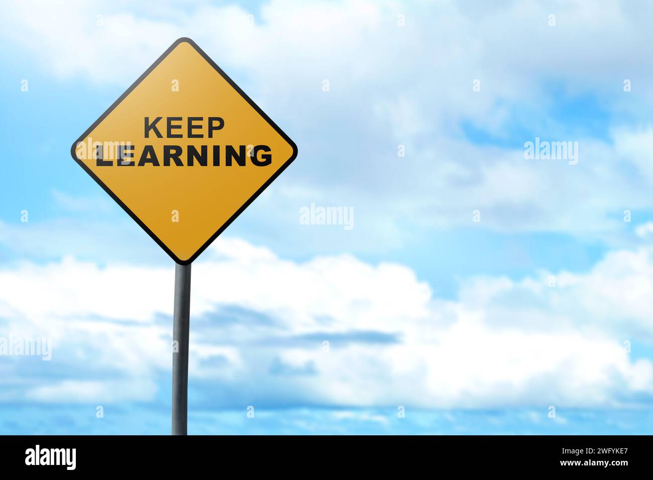 Yellow traffic sign with keep learning text and blue sky background ...