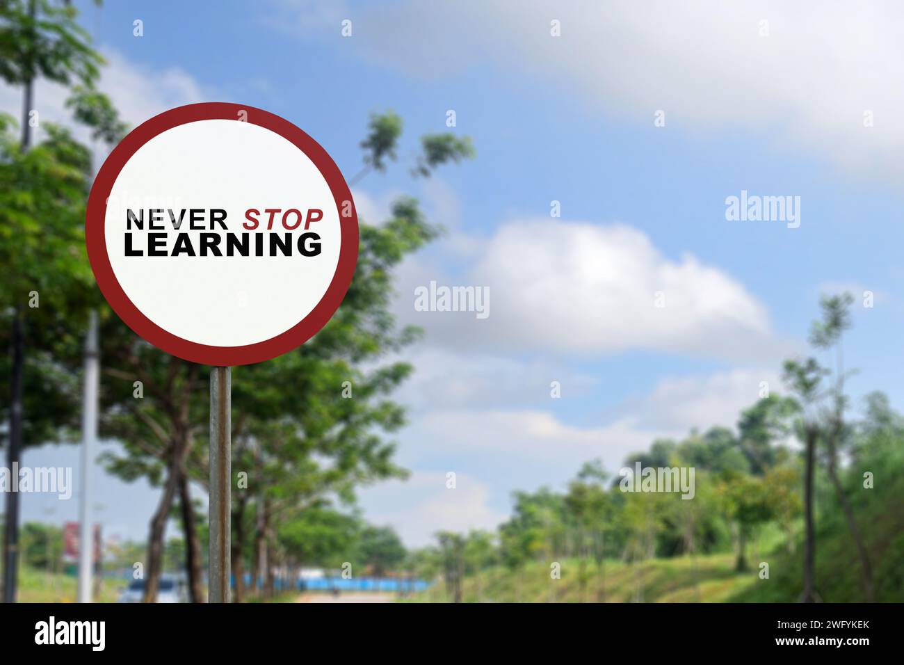 White traffic sign with text never stop learning and blue sky background. Continuous learning ...