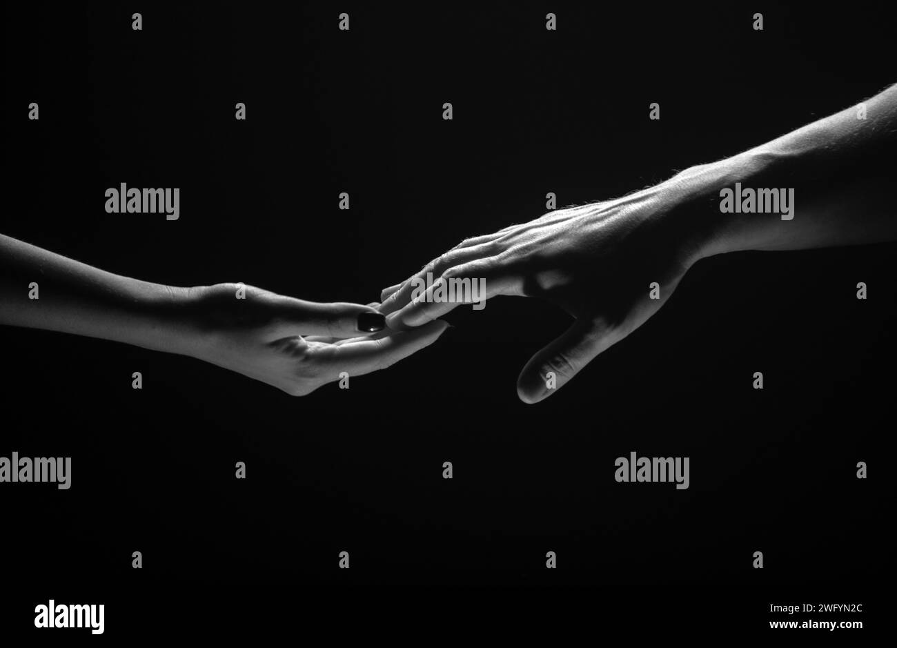 Two hands stretch each other, black background. Couple in love holding ...