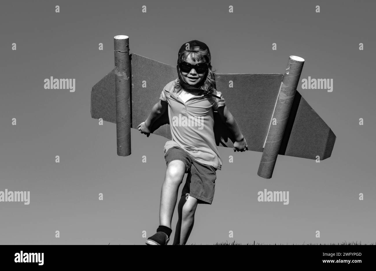 Happy child running with paper wings jumping against blue sky. Portrait ...