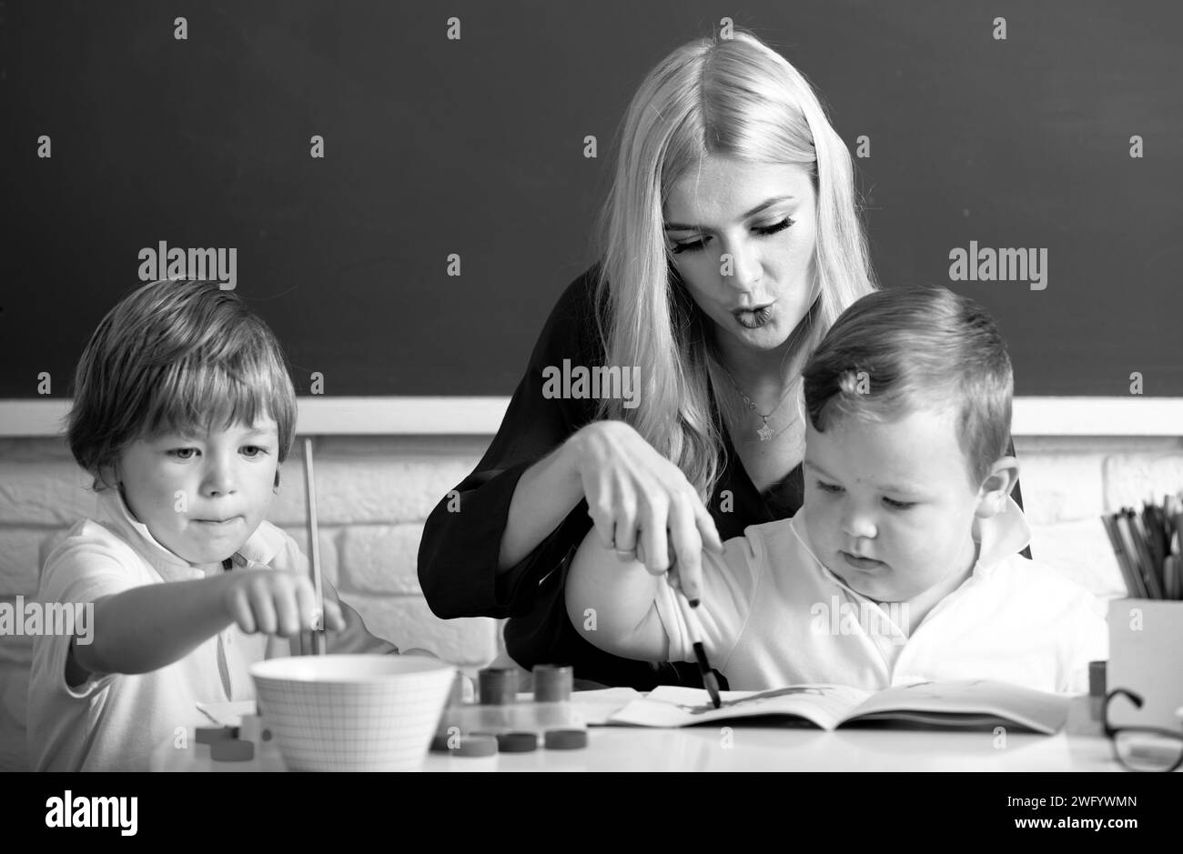 Mother and two son together draw, paint. Mom helps the children boys ...