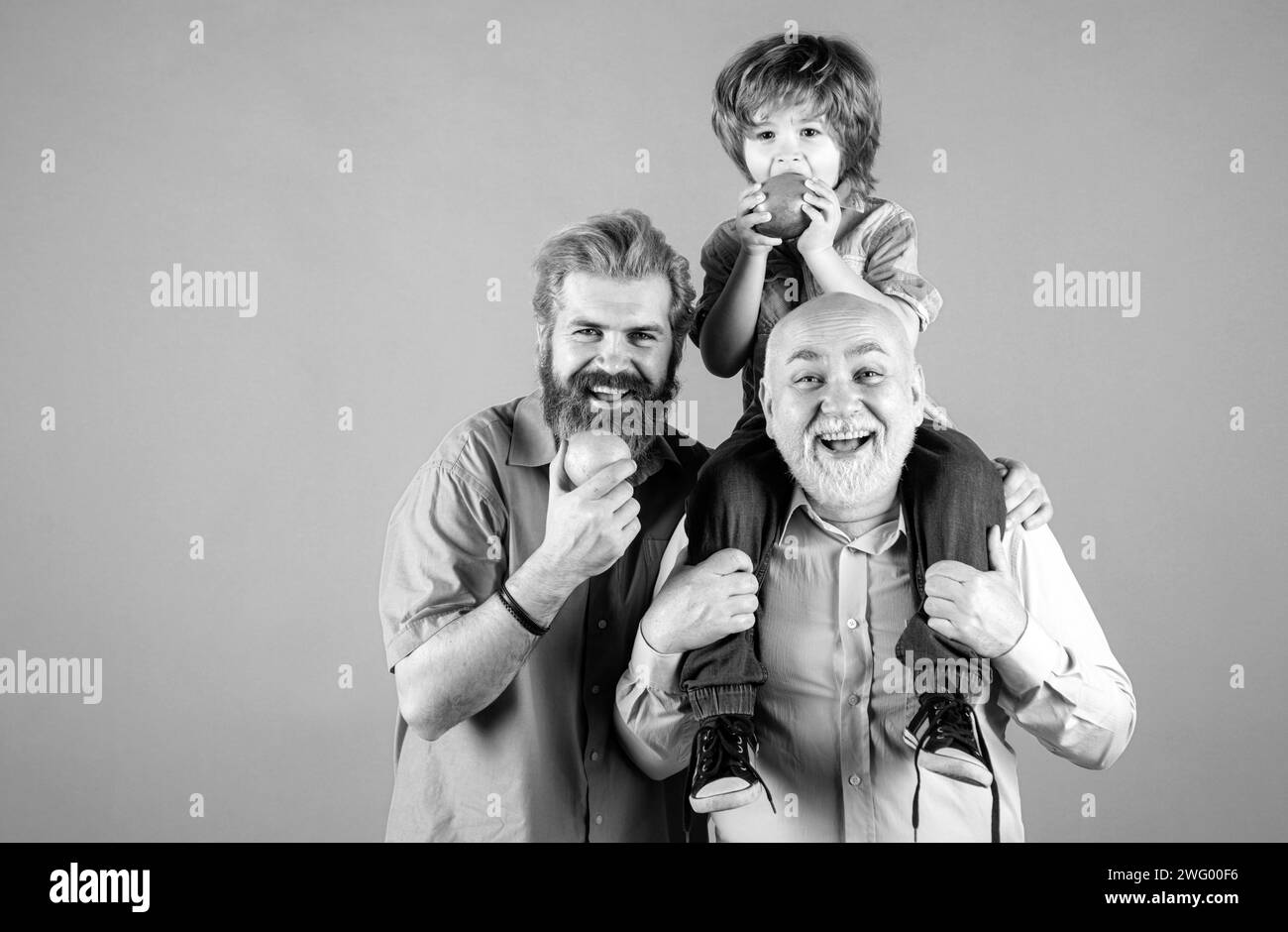 Grandfather father and son hugging and eating apple. Men in different ...