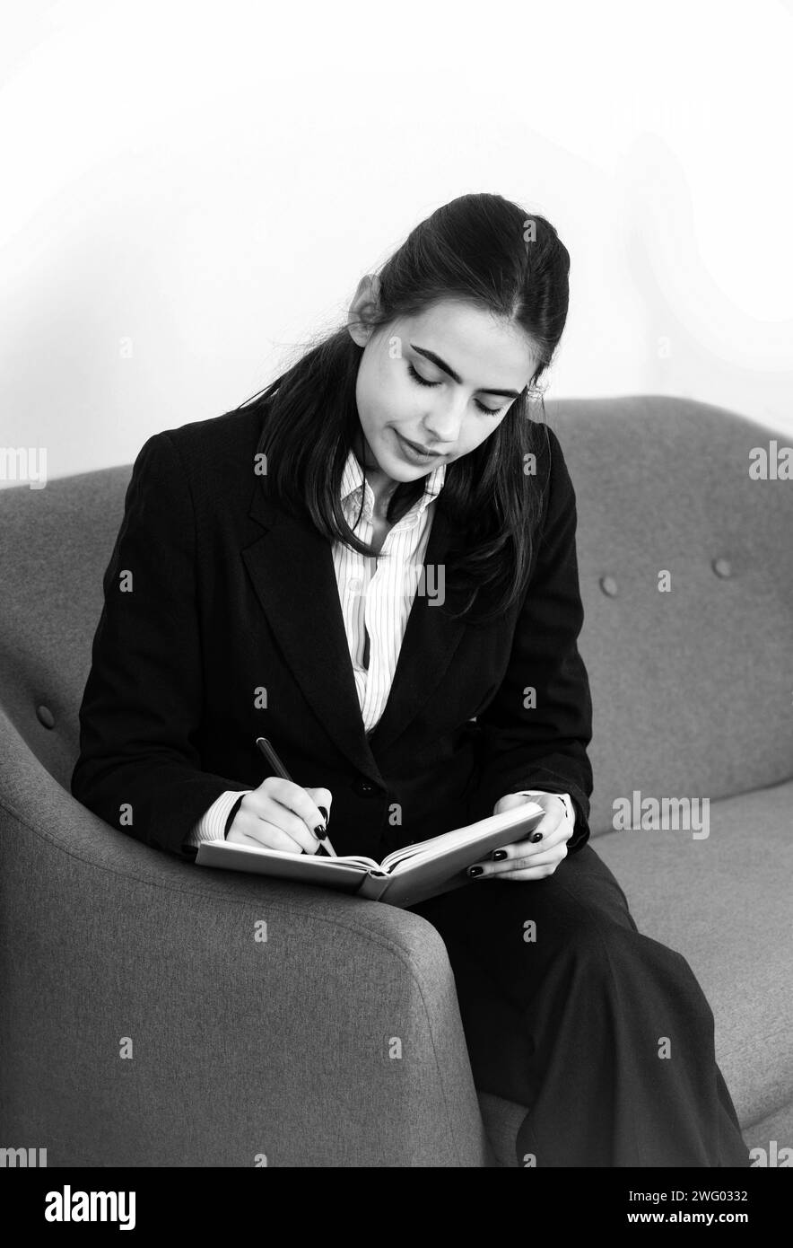 Portrait of young businesswoman accountant in formal wear making notes ...