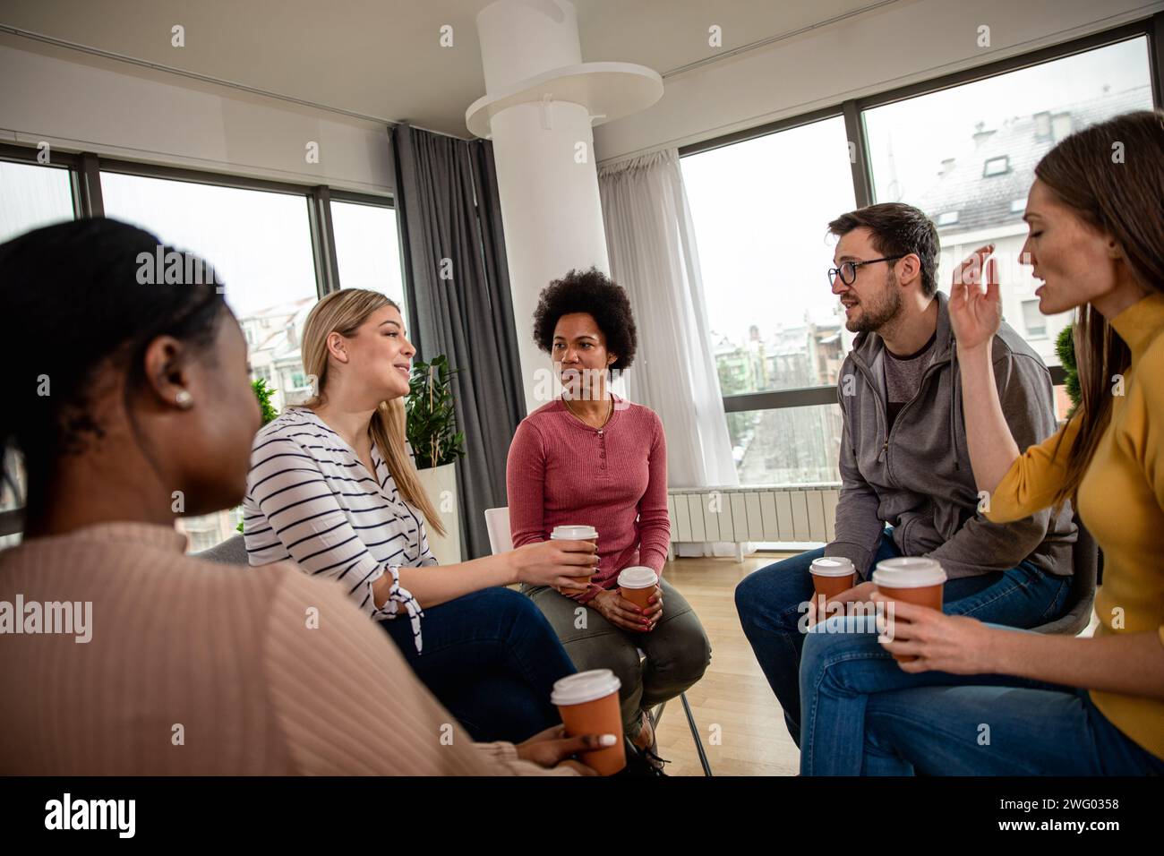 Diverse group of people sitting in circle in group therapy session ...