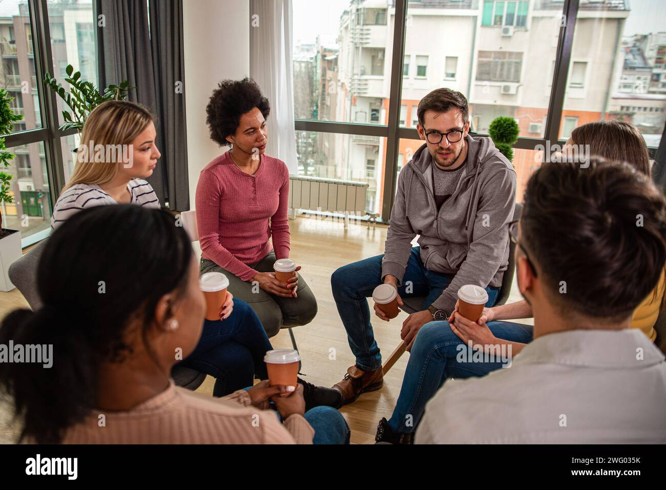 Diverse group of people sitting in circle in group therapy session ...