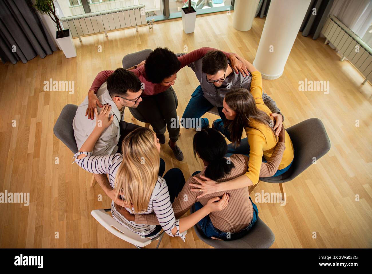 Diverse group of people sitting in circle in group therapy session ...