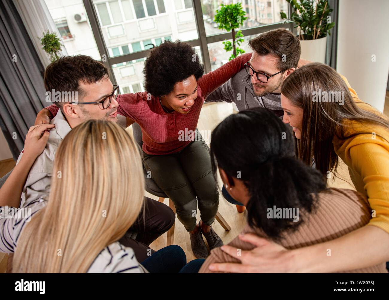 Diverse group of people sitting in circle in group therapy session ...