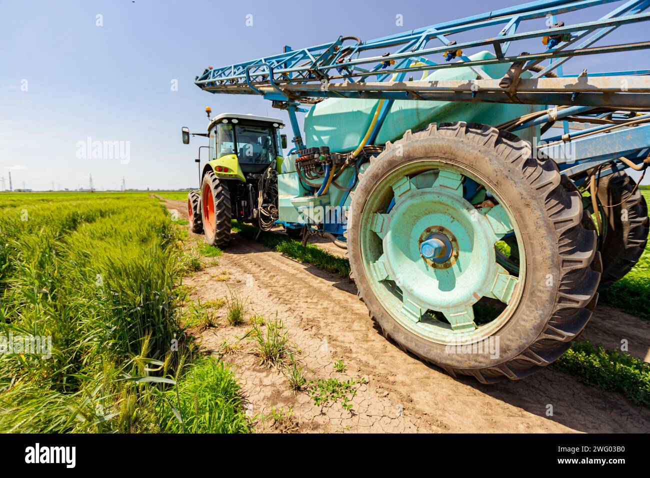 Low angle view of tractor as dragging mounted wide agricultural sprayer ...