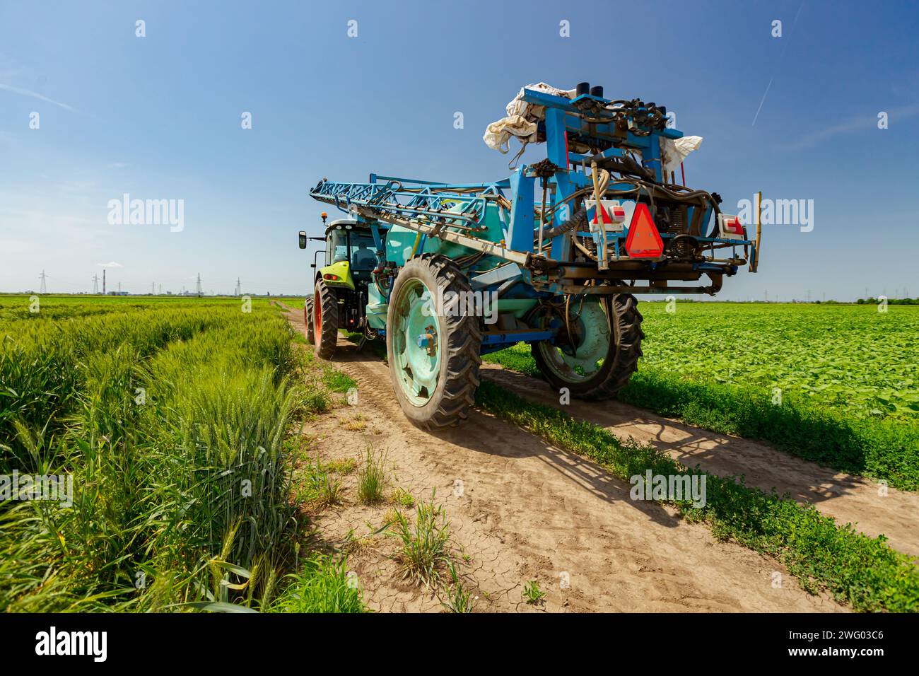 Low angle view of tractor as dragging mounted wide agricultural sprayer ...