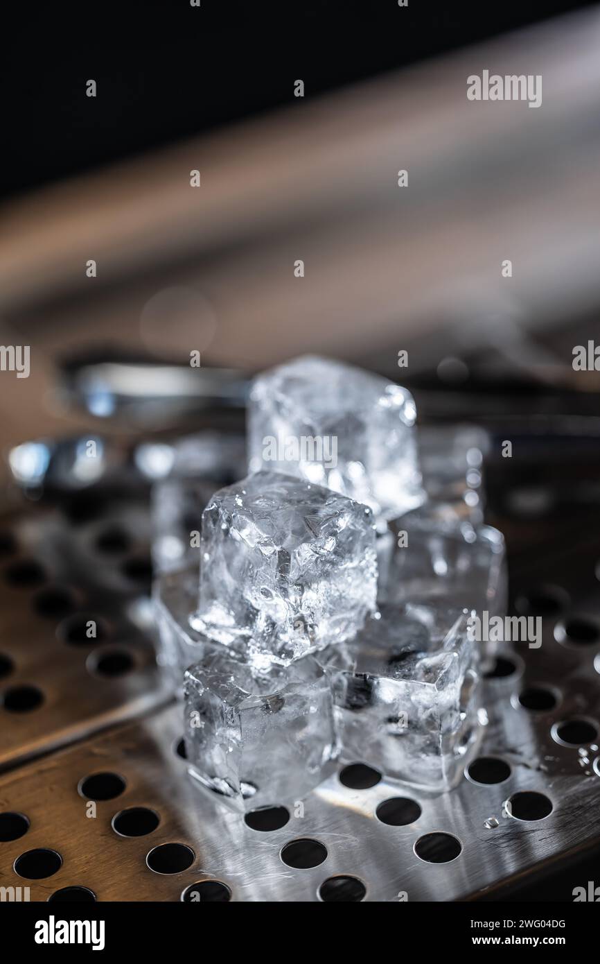Crystal clear ice cubes on the stainless steel base of the bar counter ...