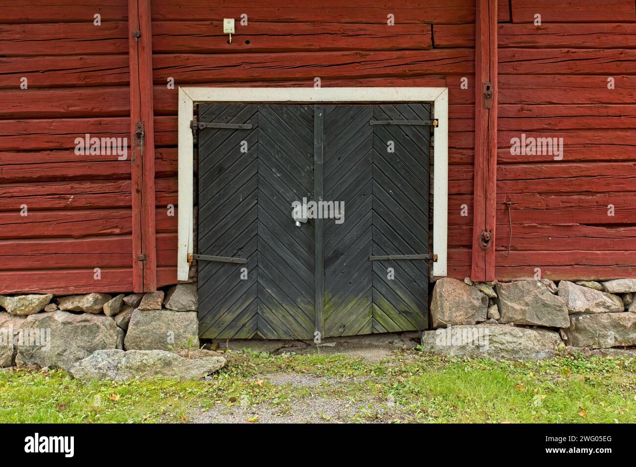 Black wooden double doors in an exterior wall of an red farm building ...