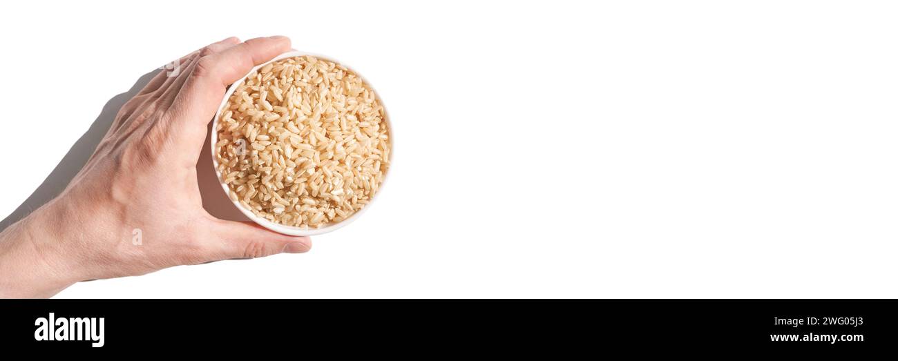 A bowl of uncooked brown rice, isolated against a white background ...