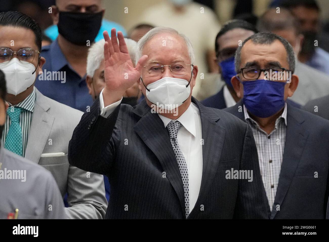 FILE - Former Malaysian Prime Minister Najib Razak, center, wearing a face mask, waves as he ...