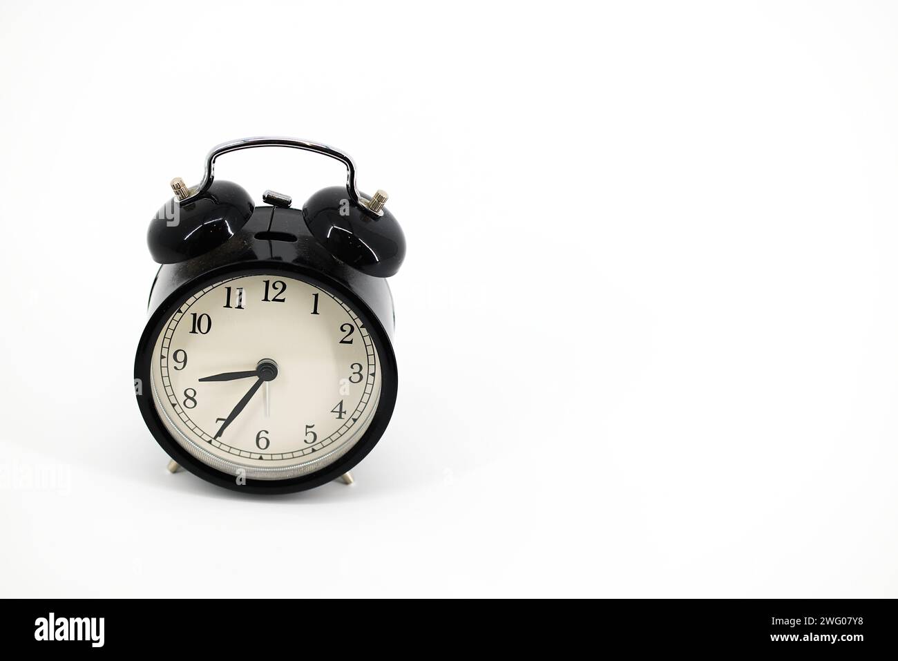A black alarm clock featuring two bells on top, chrome handle, and legs ...