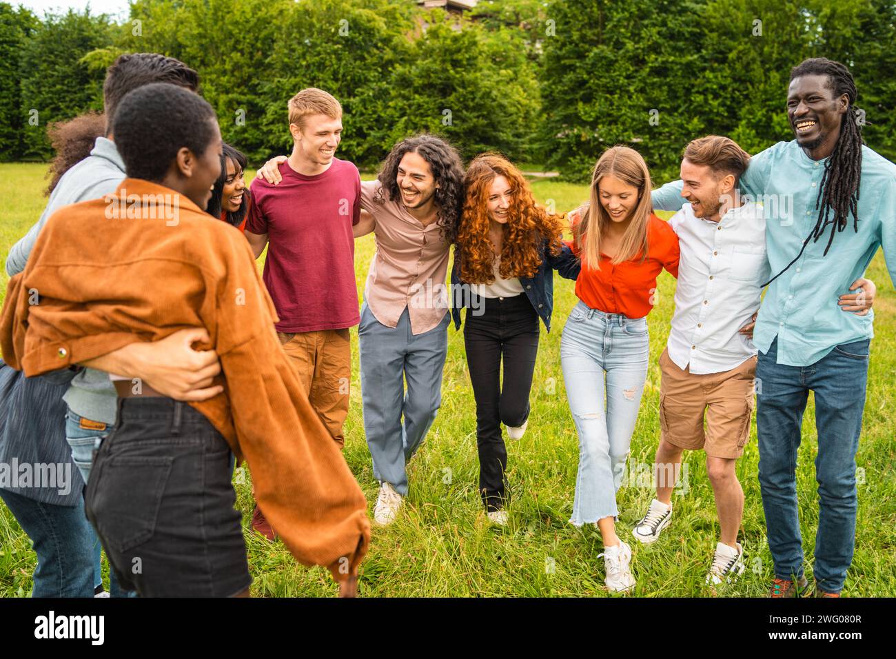 A multicultural group of young people smile and socialize in a park, a ...