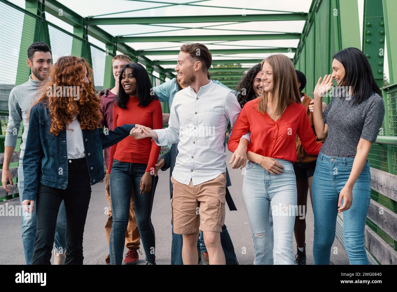 A group of multicultural friends walk relaxed and smiling on a city ...