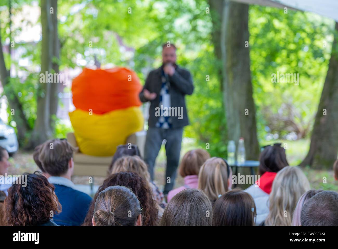 Engaged audience listening to a speaker at an informal outdoor event ...