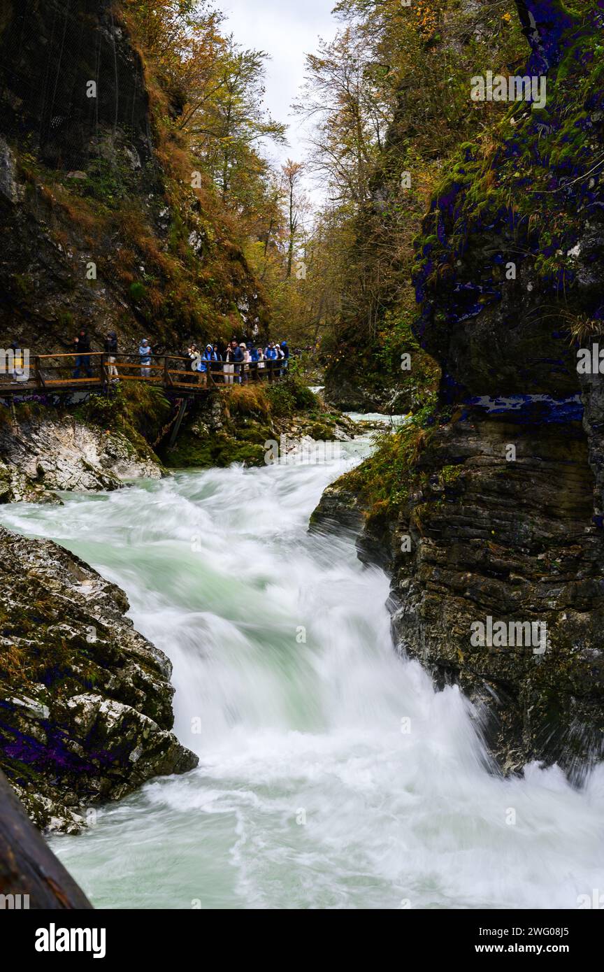 People walking on the wooden bridge across the raging river in Slovenia ...