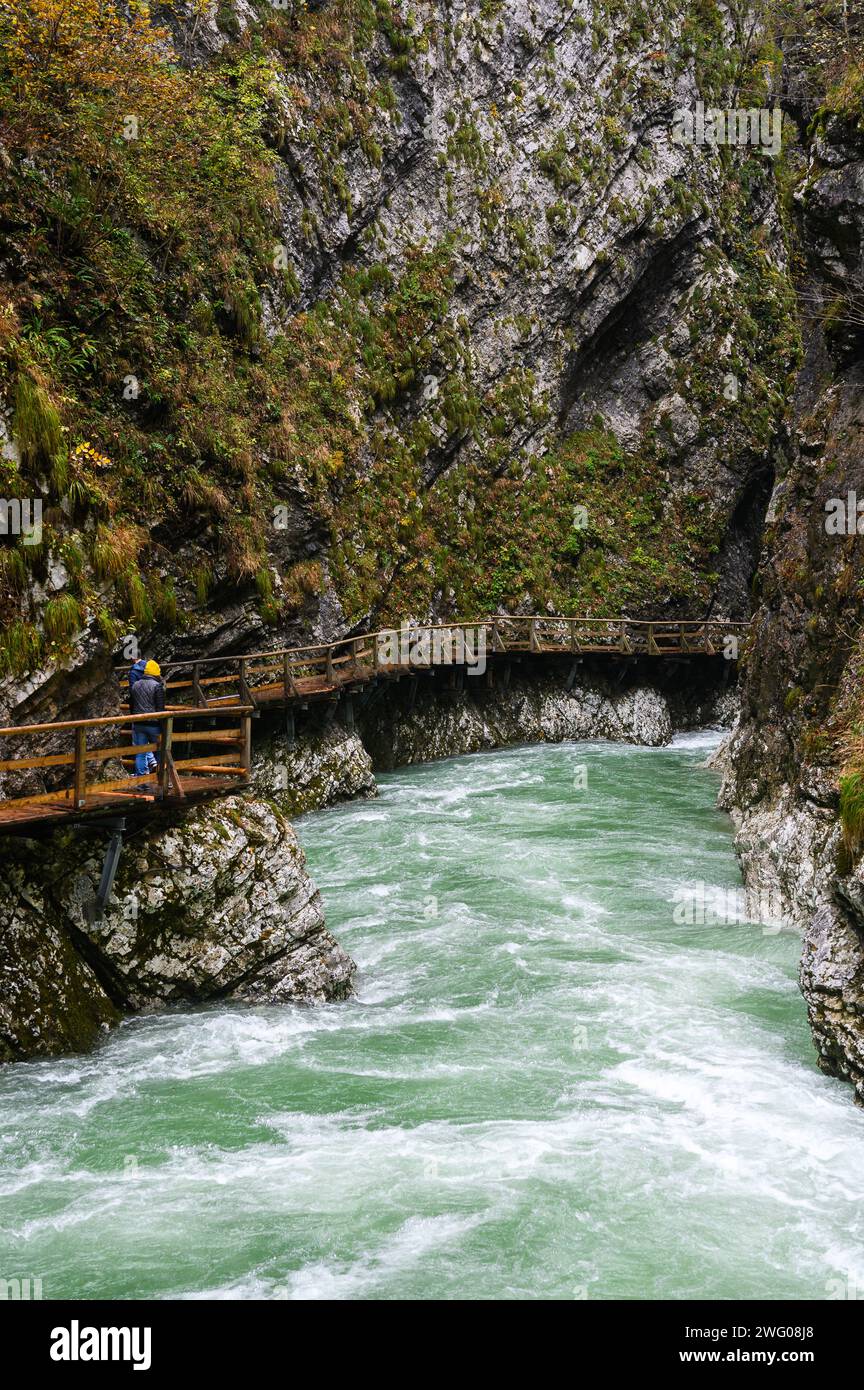 People walking on the wooden bridge across the raging river in Slovenia ...
