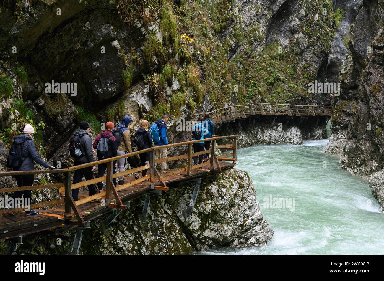 People walking on the wooden bridge across the raging river in Slovenia ...