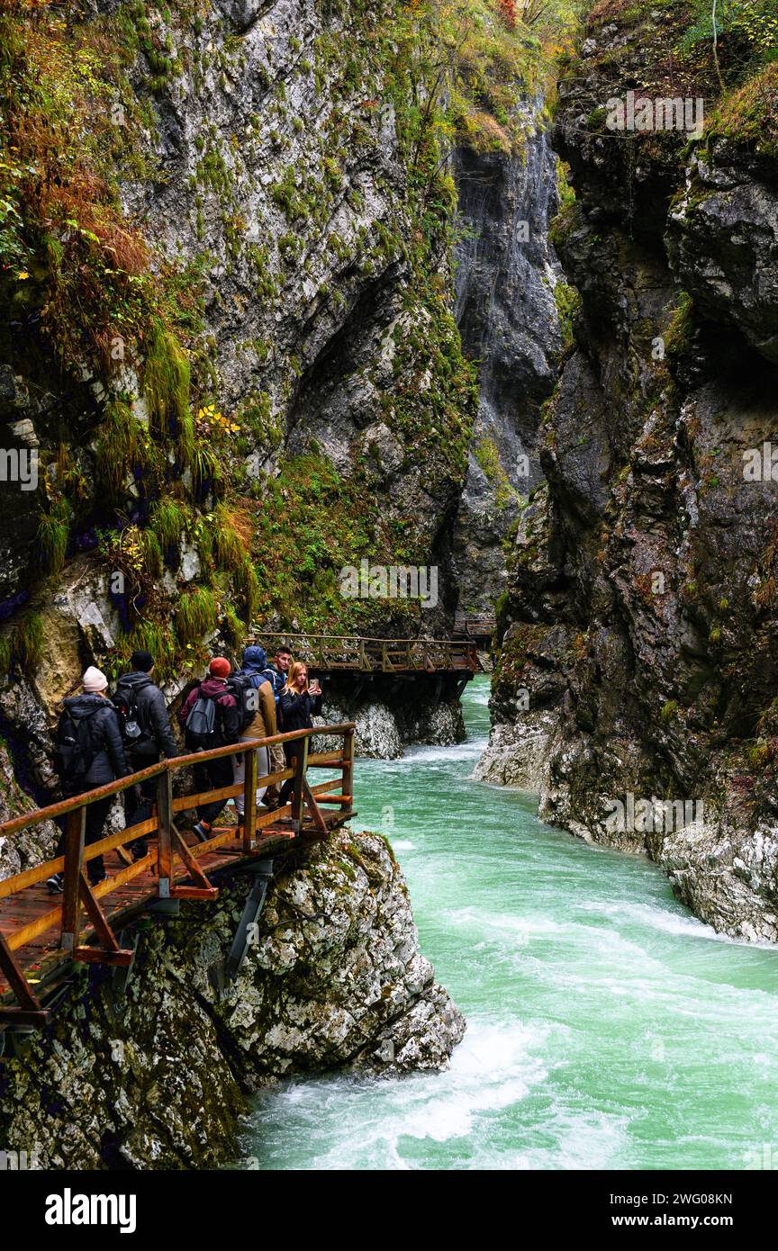 People walking on the wooden bridge across the raging river in Slovenia ...