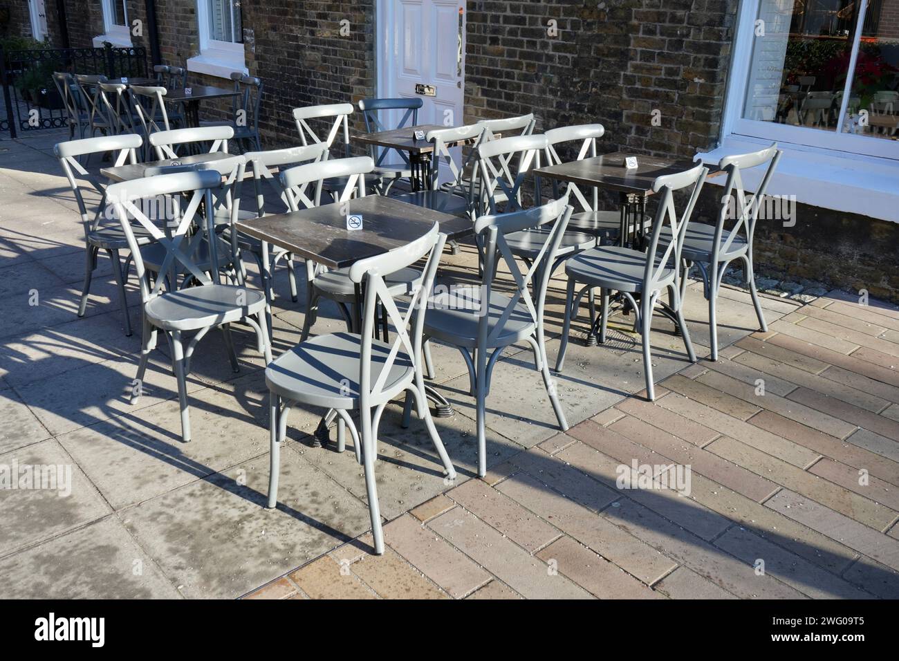 Grey cafe chairs in a London Street with red brick houses behind with ...