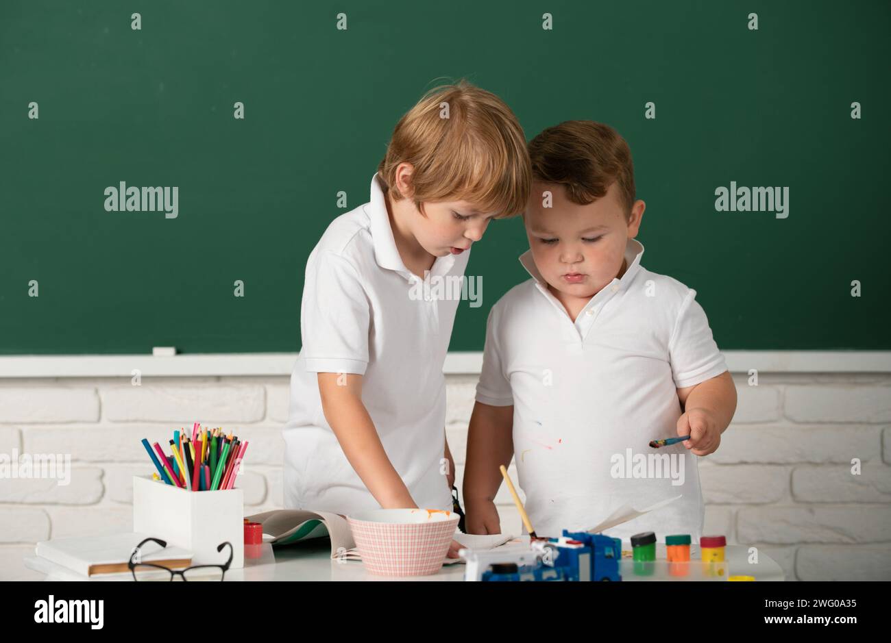 Portrait school kids bosy doing art homework, holding pencil, writing ...