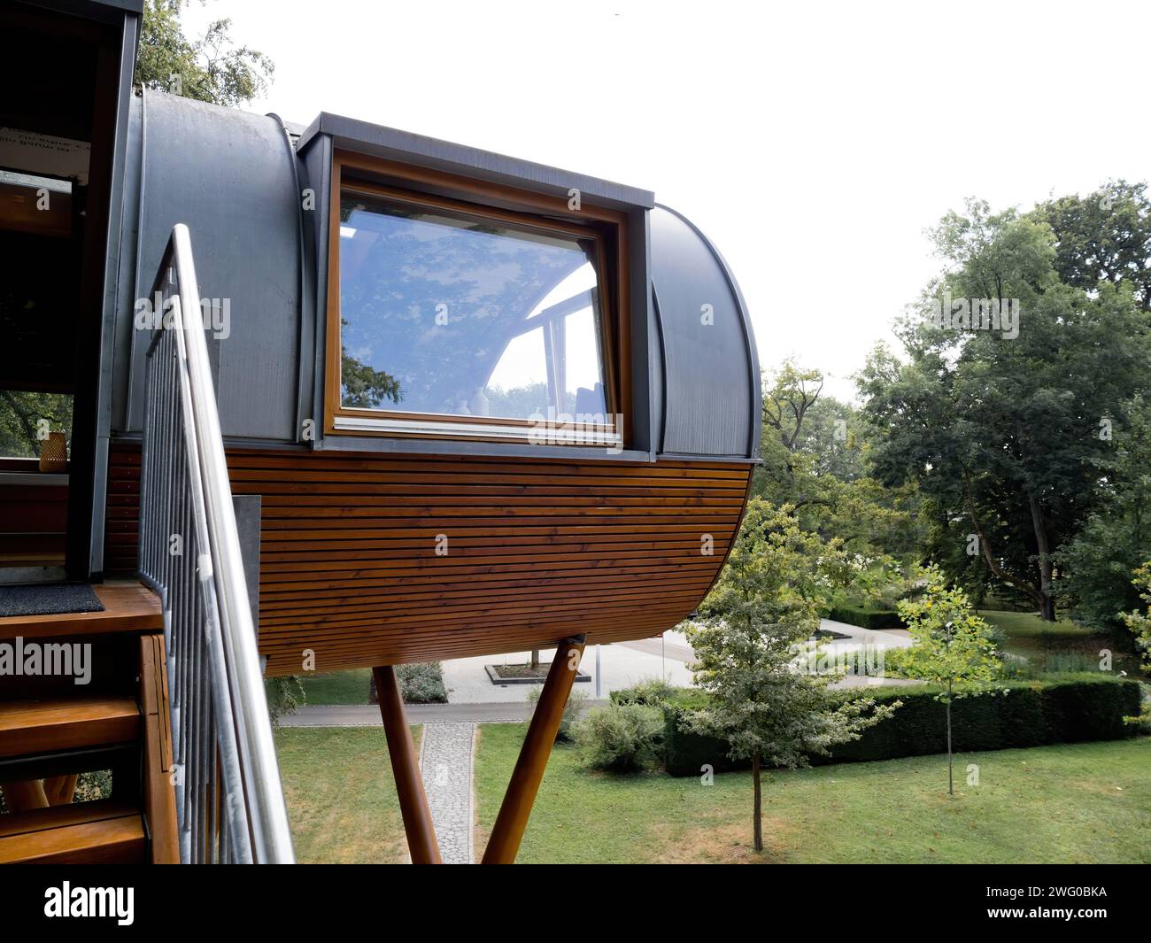 Unique wooden treehouse with large windows, situated in a green park ...