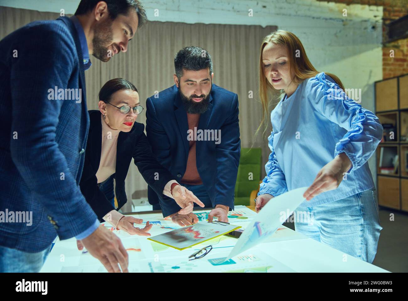 Group of professionals, colleagues engaged in strategic planning session with graphs and charts ...