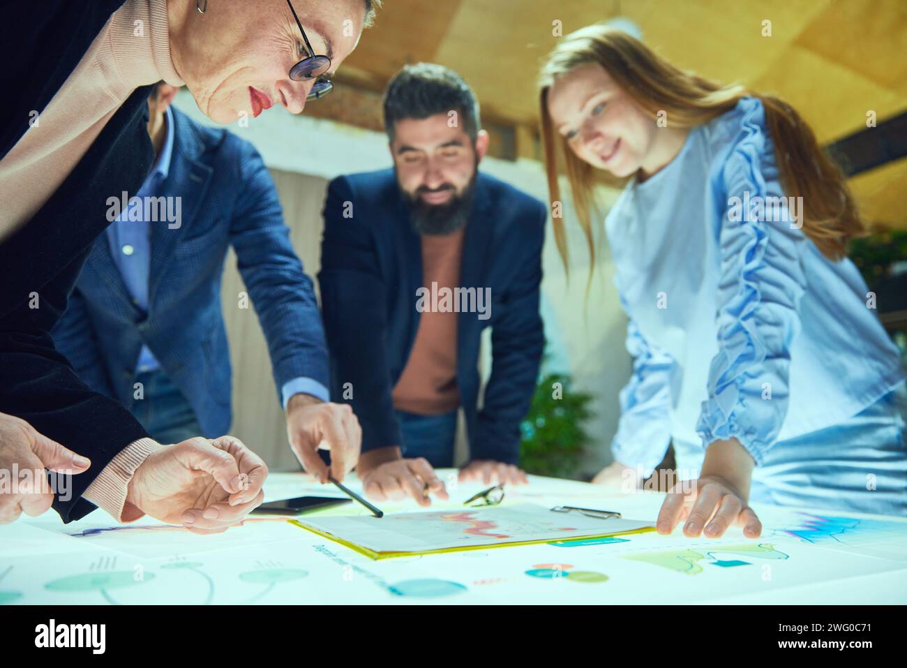 Group of professionals, colleagues engaged in strategic planning session with graphs and charts ...