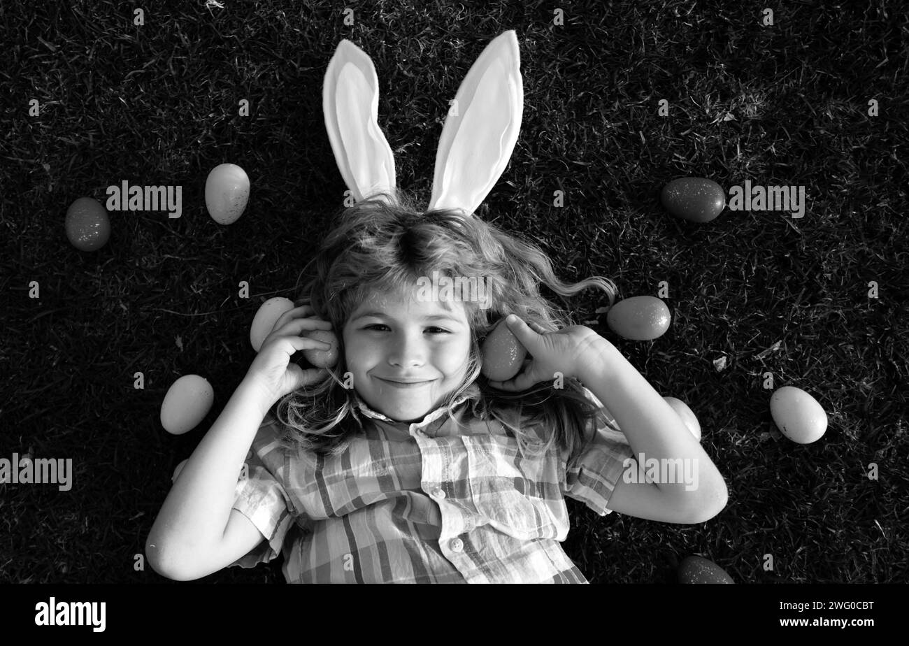 Kid boy hunt egg on Easter day outdoor. Top view funny kids laying on ...