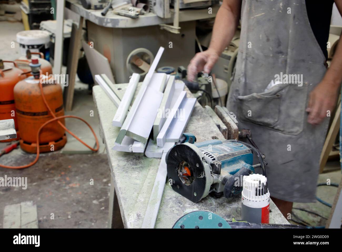 Man in apron using power tools in workshop Stock Photo - Alamy