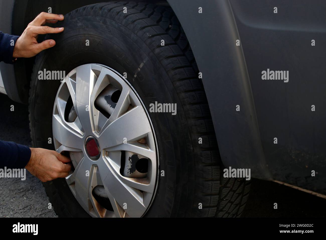 Man installing tire with thumb resting under wheel Stock Photo - Alamy