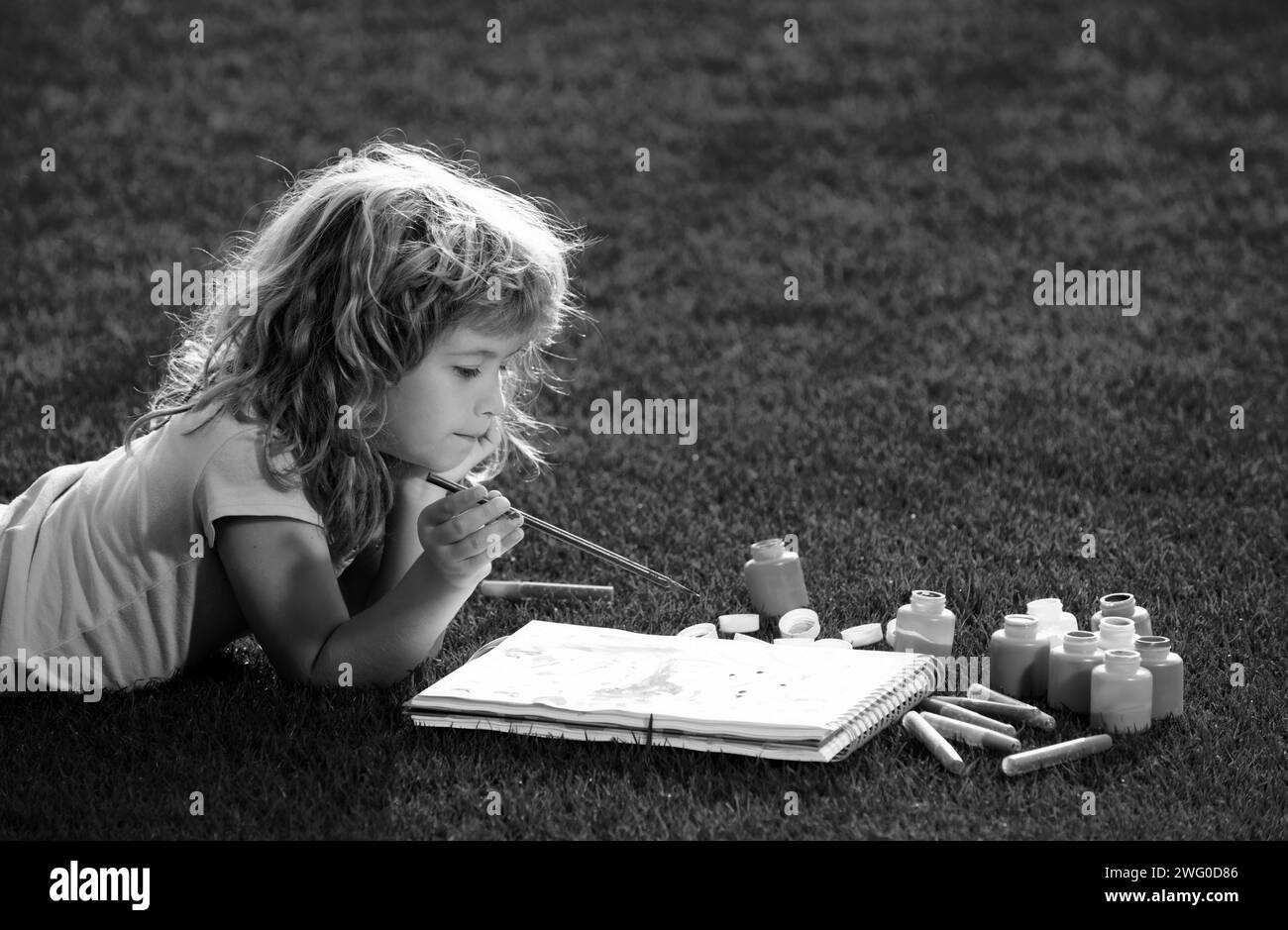 Child painting drawing art. Child boy draws in park laying in grass ...