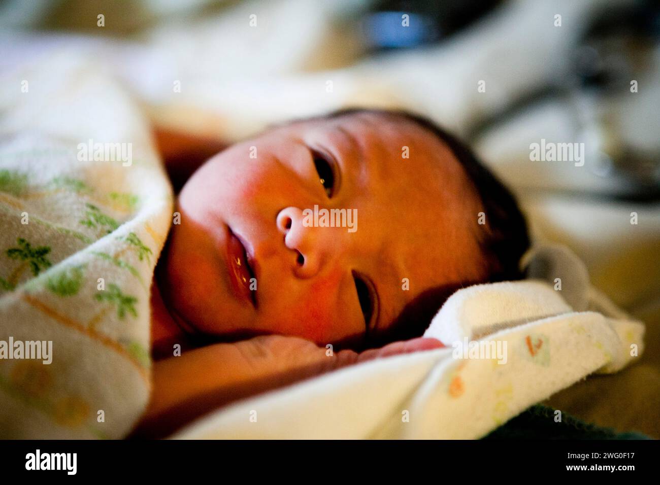 A newborn baby boy lays in bed while midwives preform their newborn ...