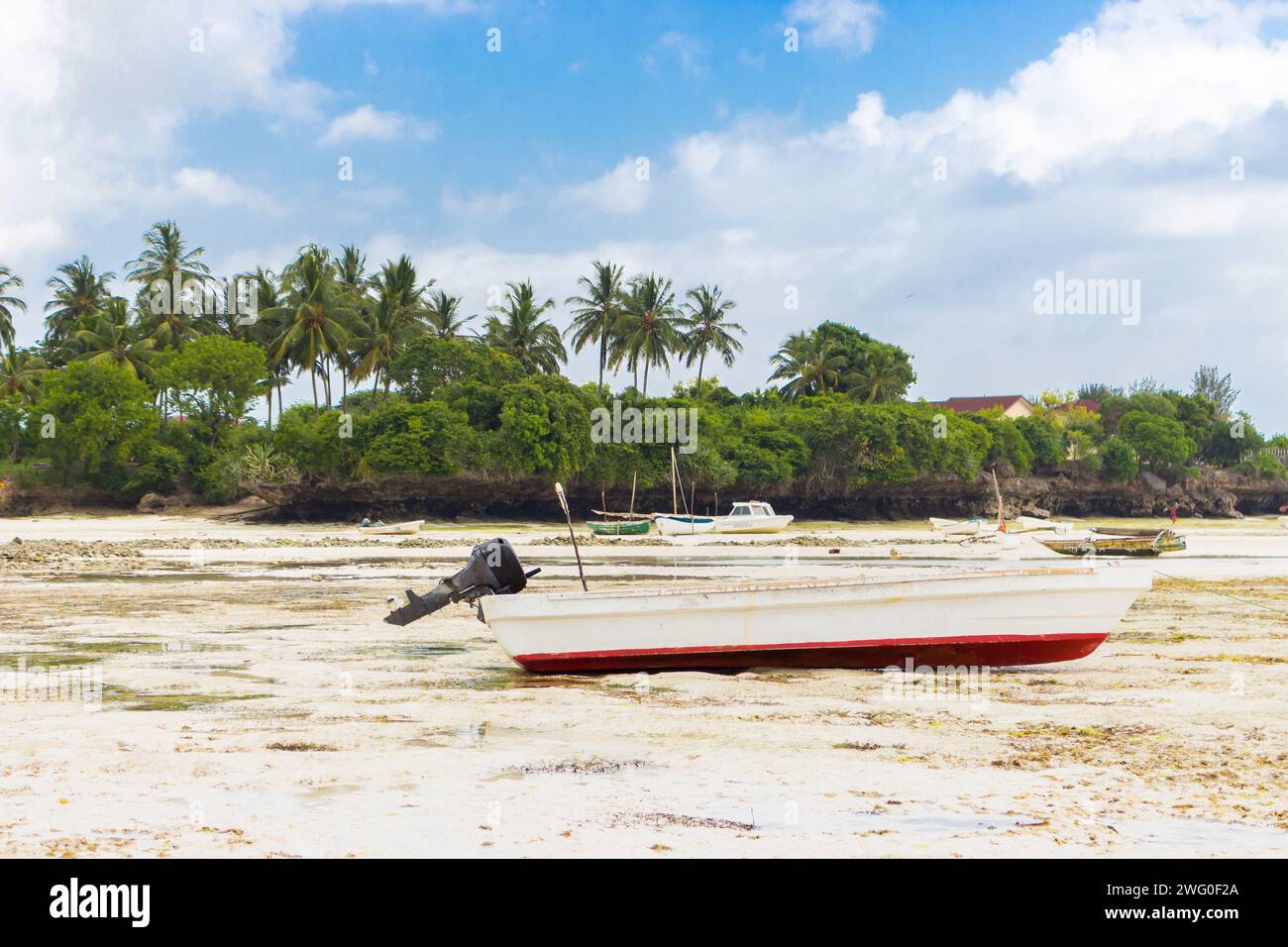 Motor boat anchored at the beach. Tropical low tide landscape with sailboats. Nautical vessel on ...