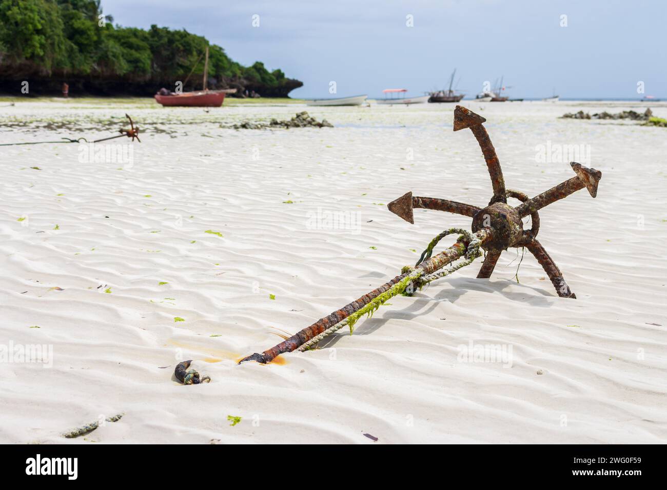 Boat anchor on the beach. Low tide beach with rusty anchor and boats ...