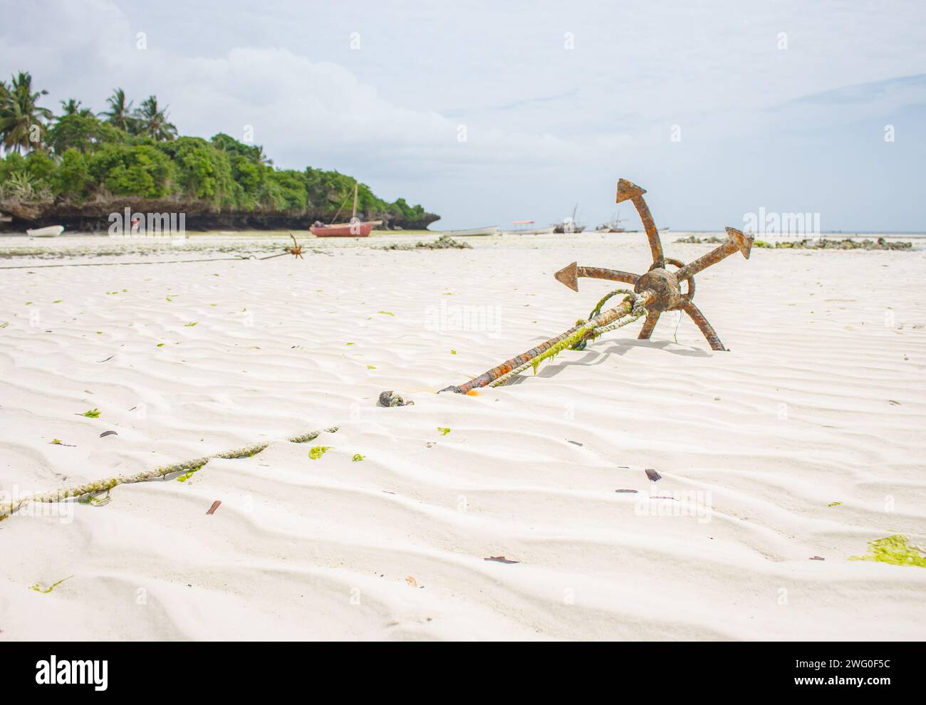 Boat anchor on the beach. Low tide beach with rusty anchor and boats ...