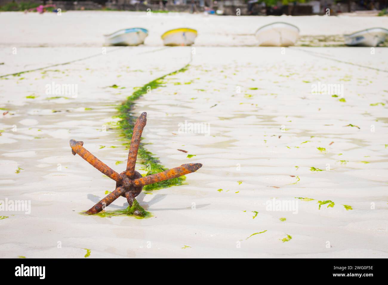 Boat anchor on the beach. Low tide beach with rusty anchor and boats ...