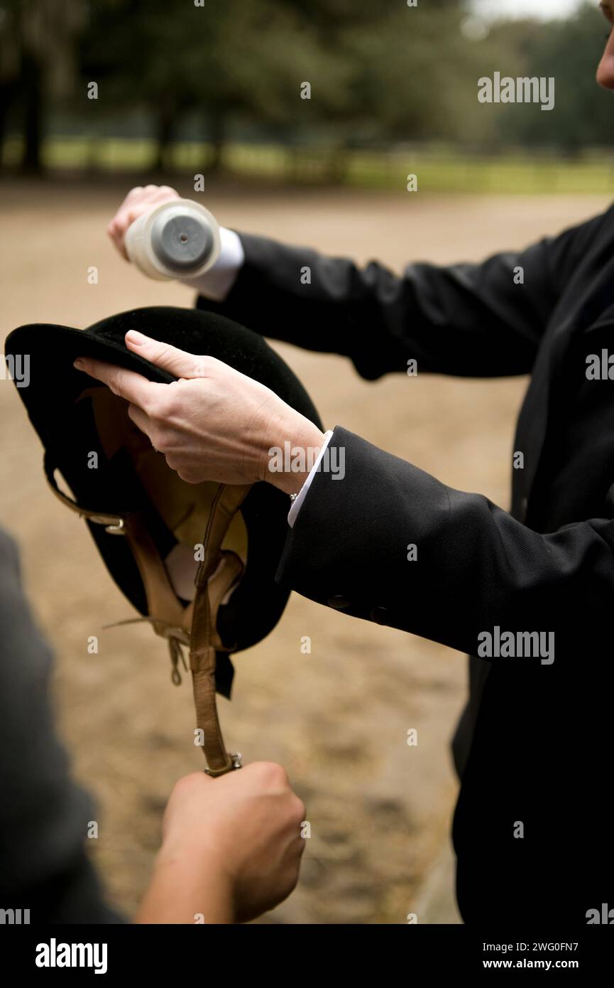 A woman lint rolls her riding helmet before a traditional fox hunt ...