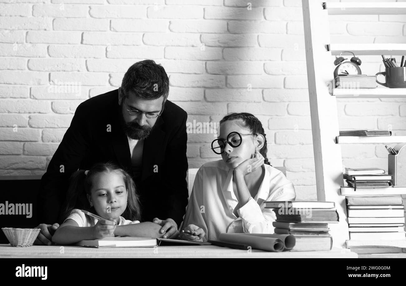 Portrait of father tutor and school kids daughters at school. Reading ...
