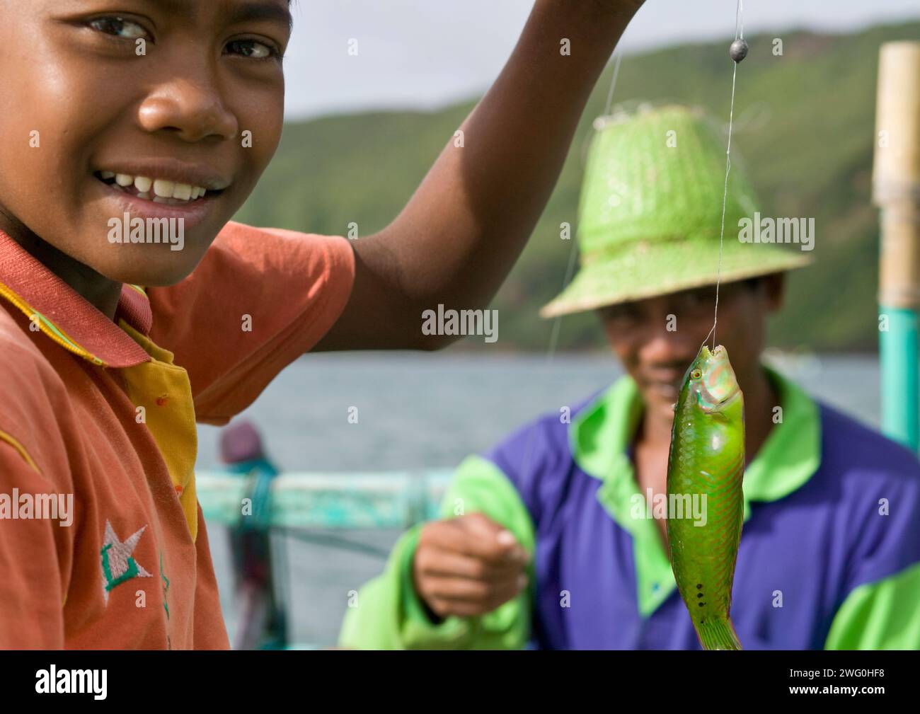 A boy shows off a fish that he has caught near Kuta, Lombok, Indoensia ...