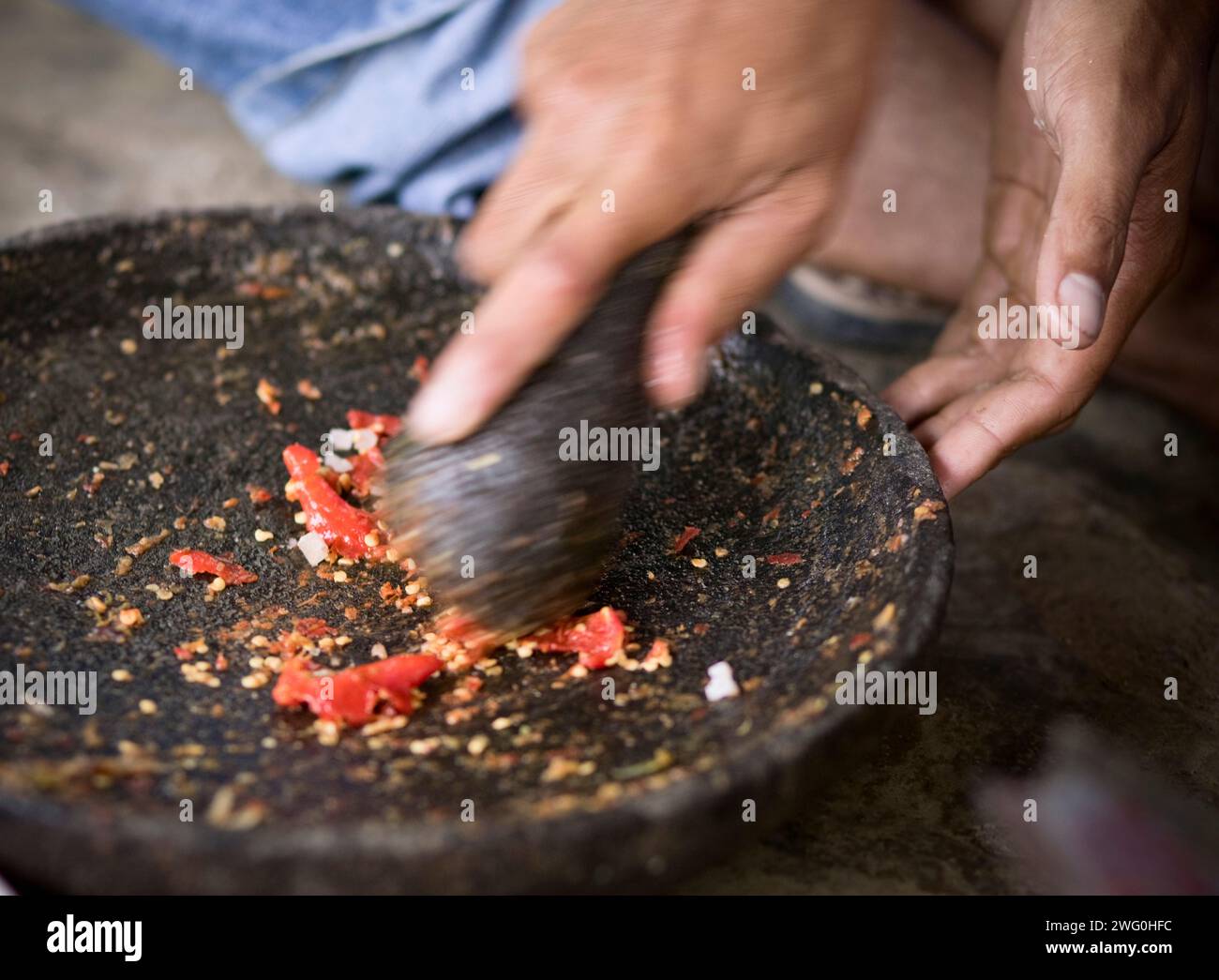 An Indonesian man crushes some chili peppers for dinner, Lombok ...