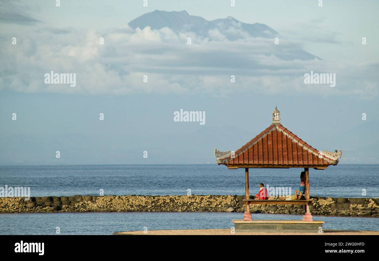 A family rests in Nusa Dua, Bali, Indonesia with the shadow of Gunung ...