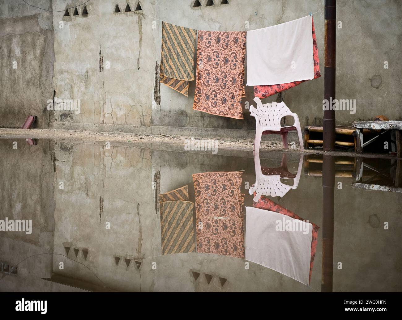 A plastic chair and laundry are reflected in a puddle on Gili Trawangan ...
