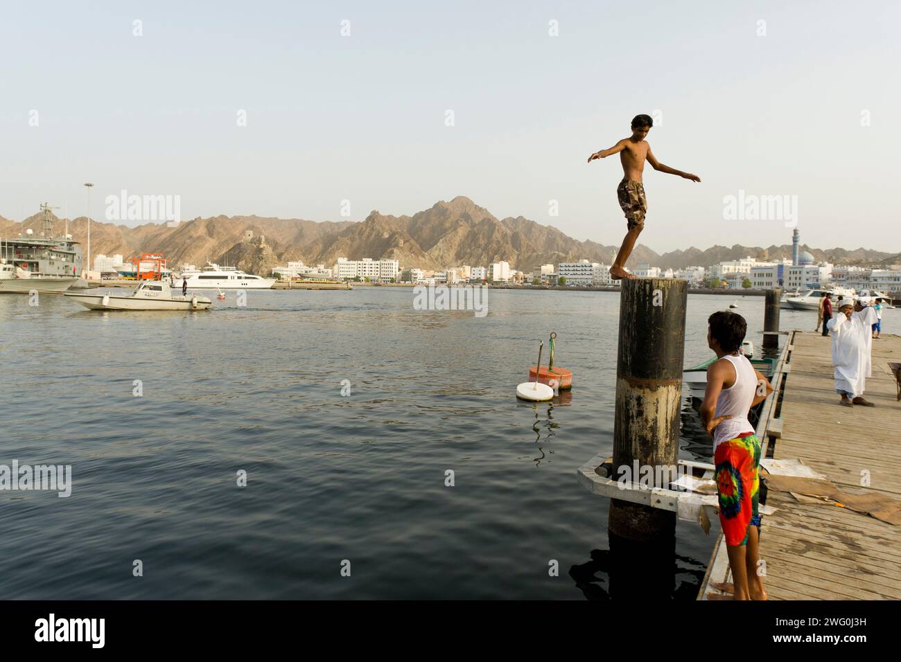 A boy dives into the water of Sultan Qaboos Port in Muscat, Oman Stock ...