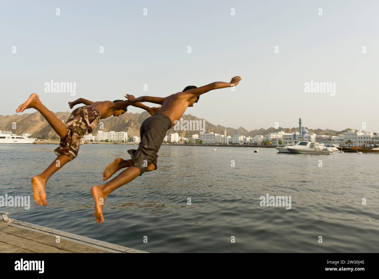 Two boys dive into the water of Sultan Qaboos Port in Muscat, Oman ...